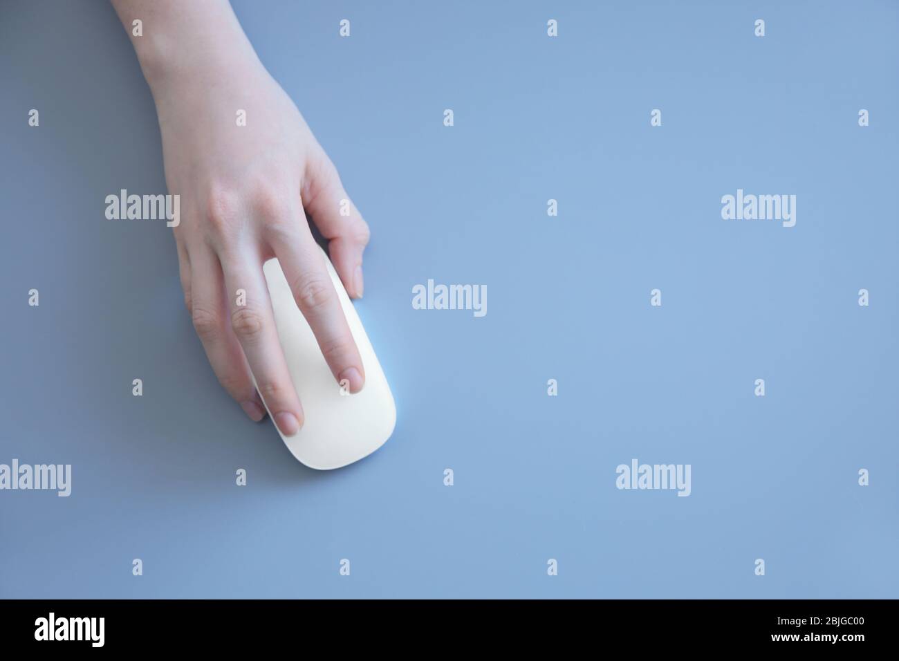 Female hand holding computer mouse on grey background Stock Photo - Alamy