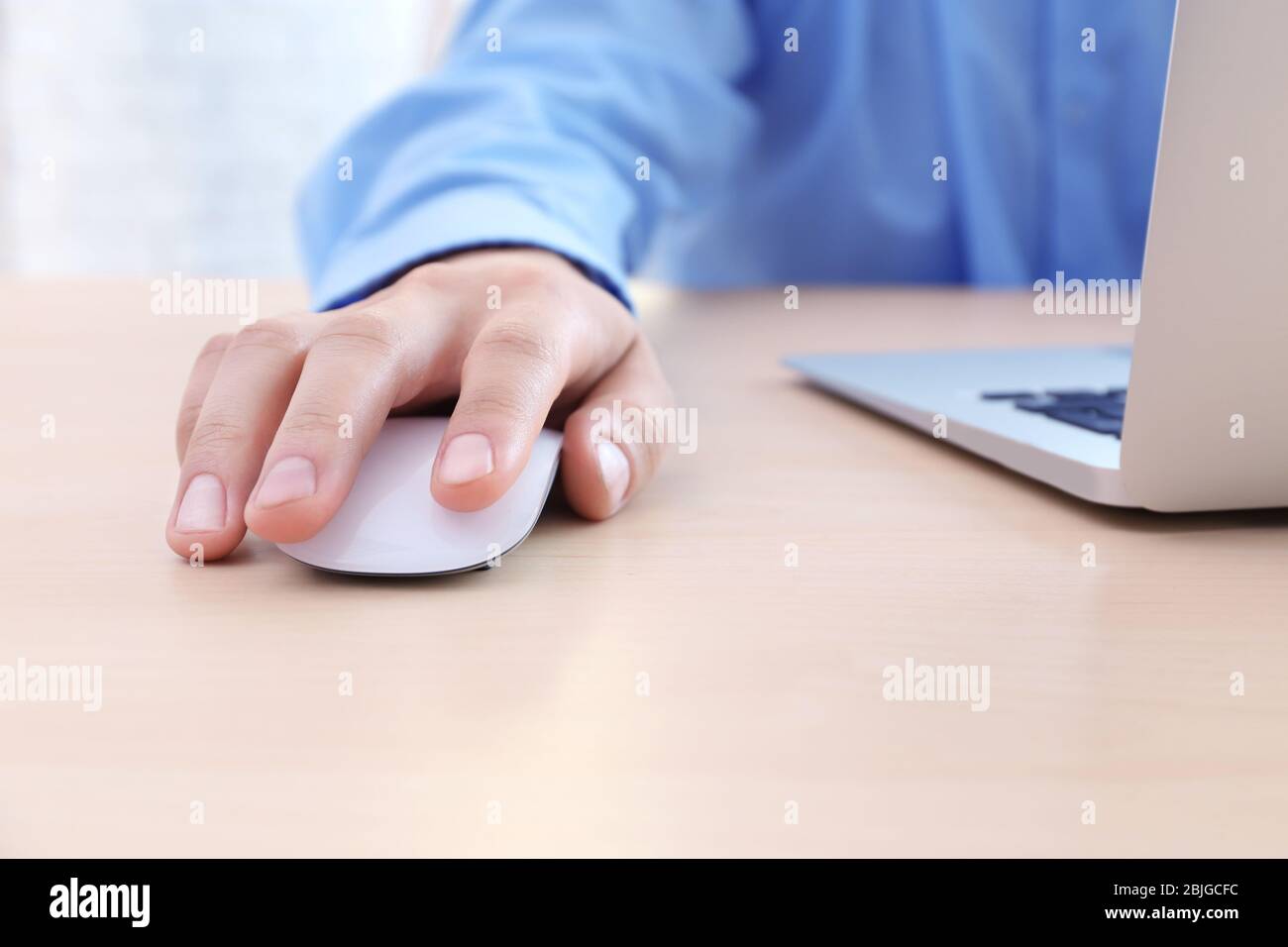 Male hand with computer mouse and laptop on table Stock Photo - Alamy