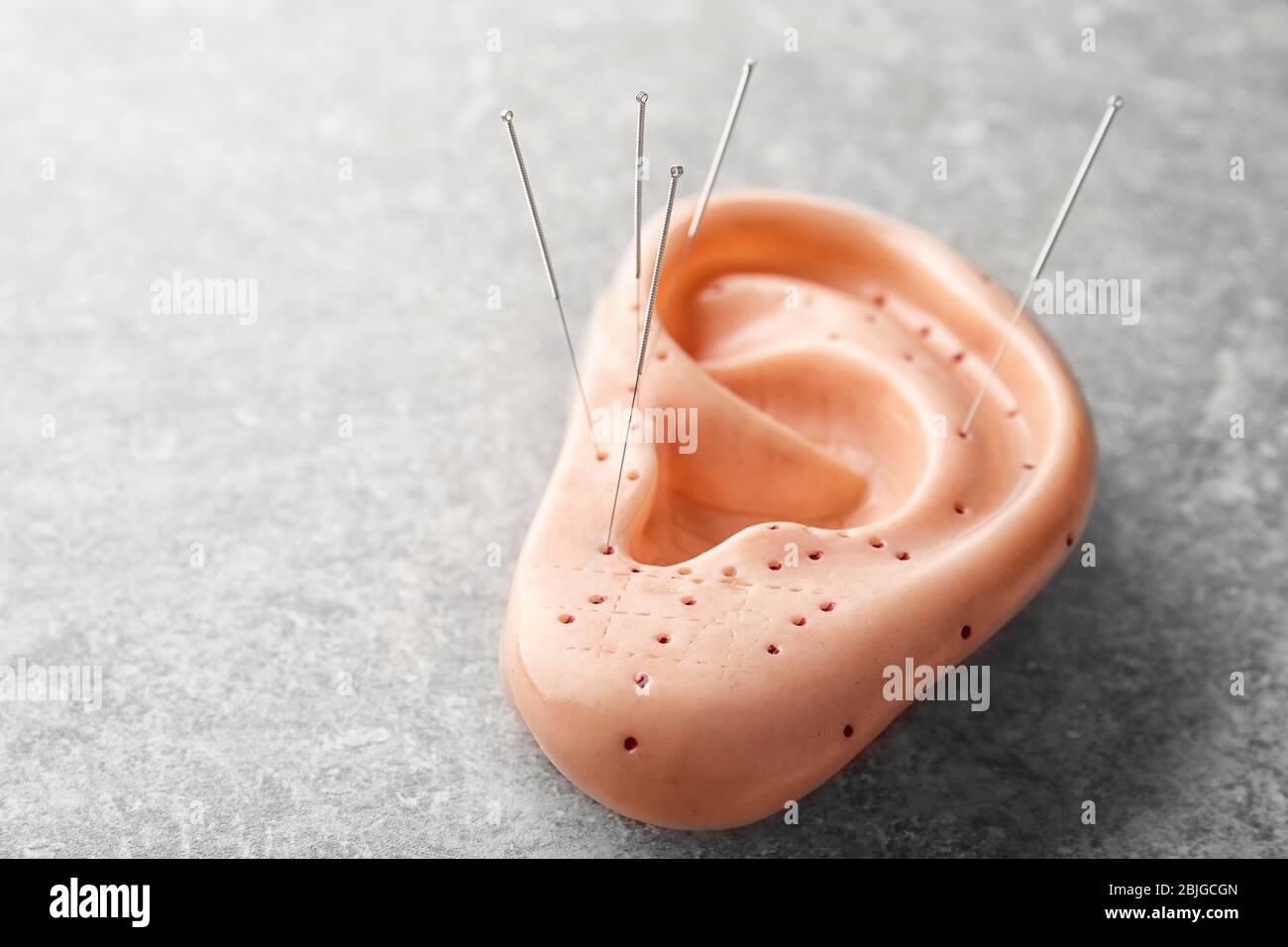 Needles for acupuncture and plastic mockup of human ear on grey ...