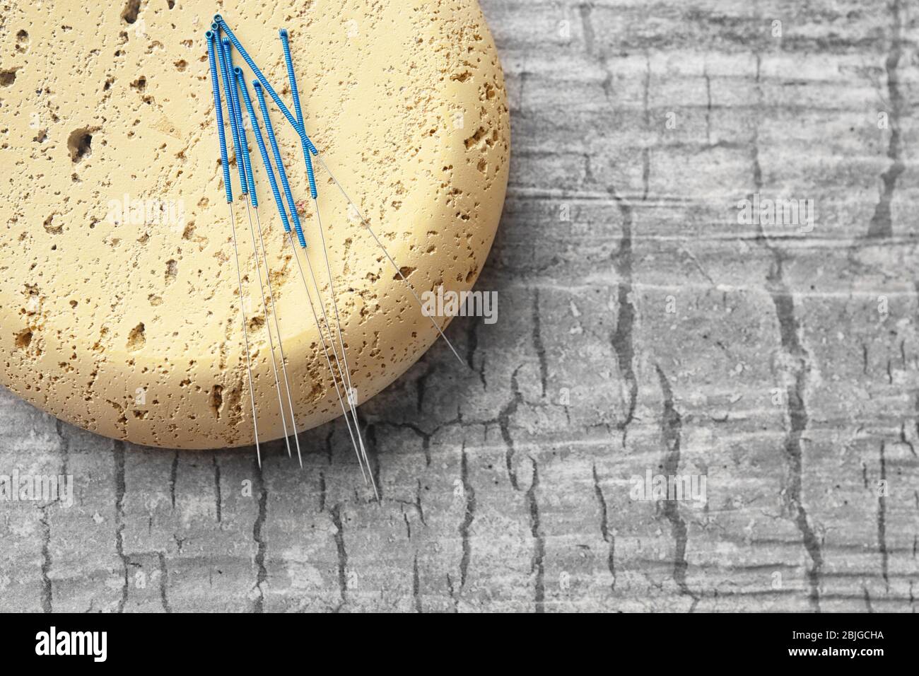 Stone and needles for acupuncture on grey background Stock Photo - Alamy