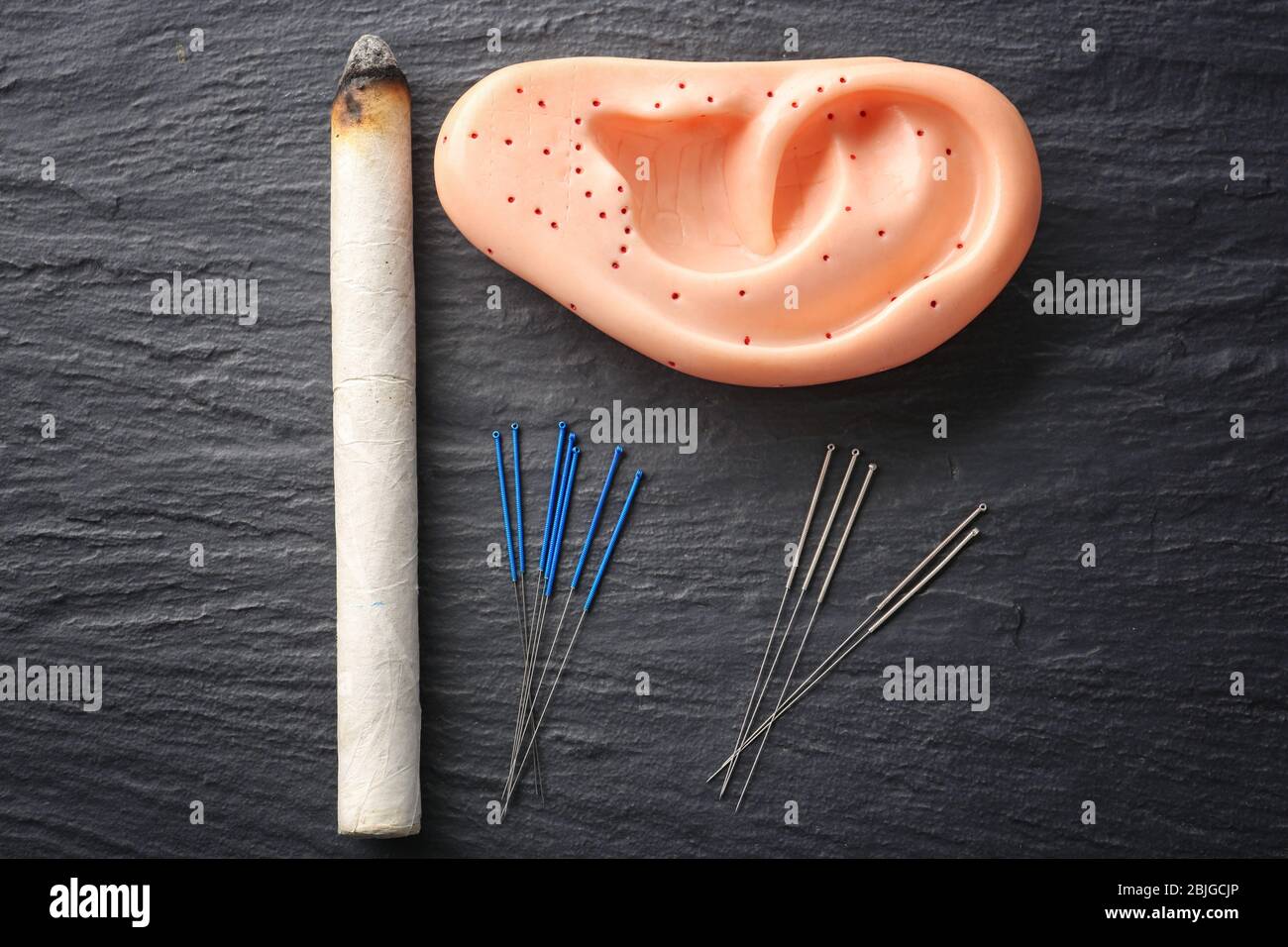 Moxa stick, needles for acupuncture and plastic mockup of human ear on ...
