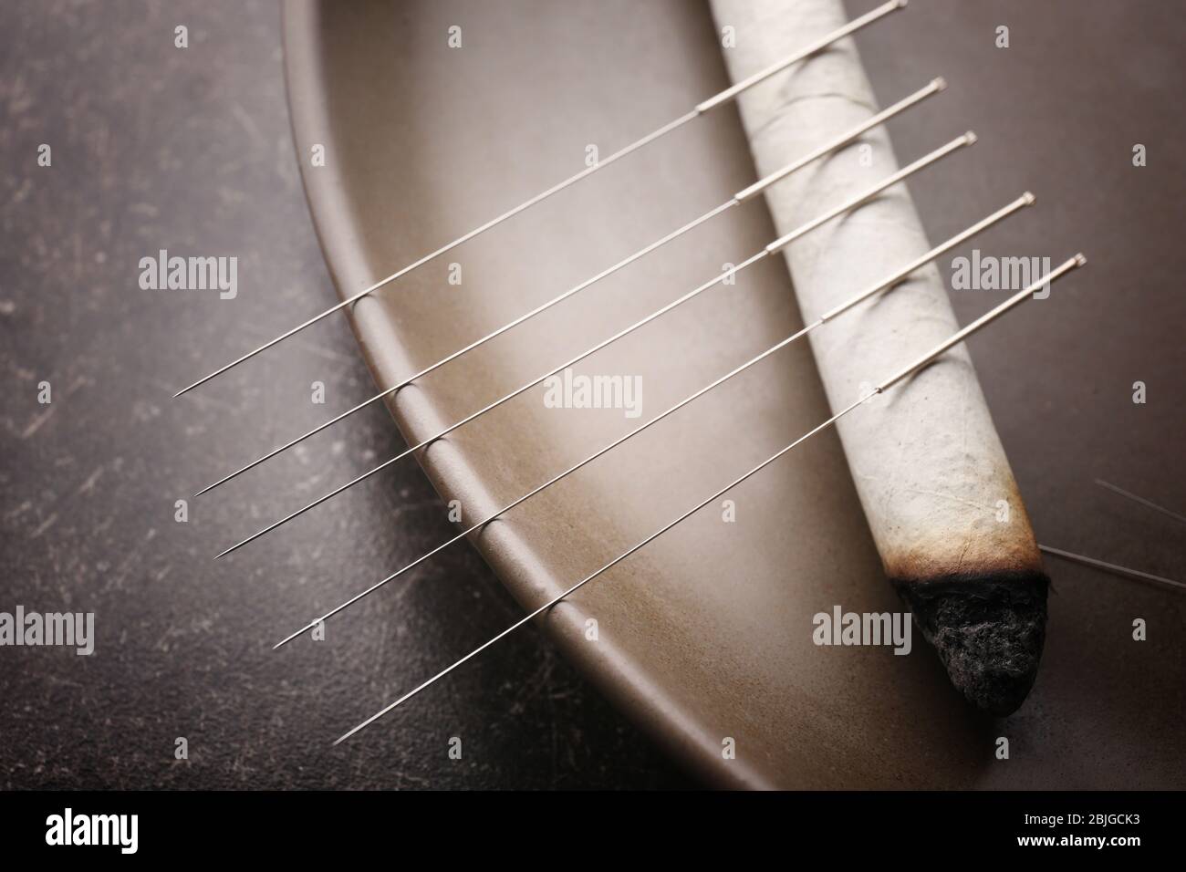 Plate with moxa stick and needles for acupuncture on dark textured ...