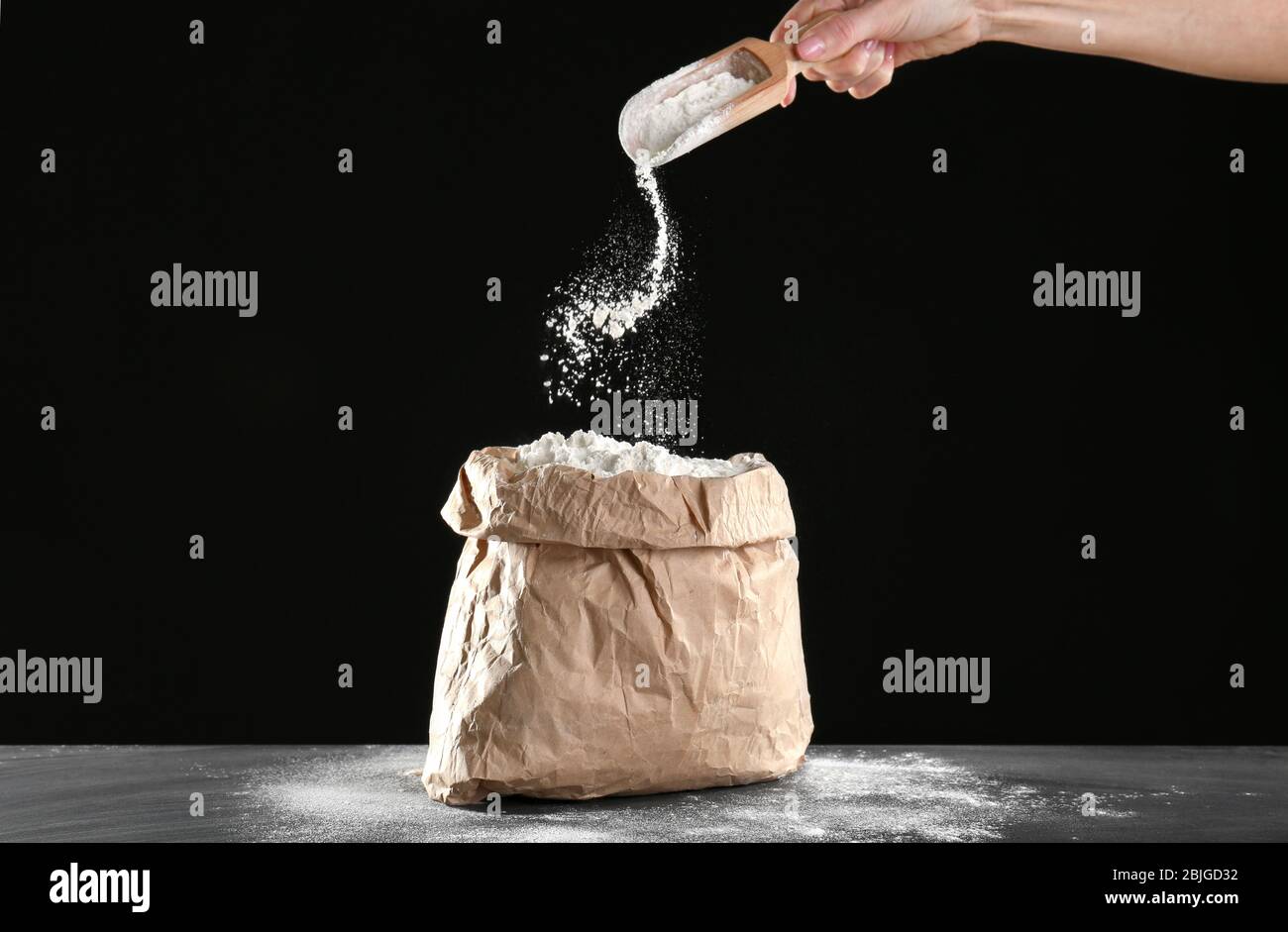 Bag of flour and female hand with scoop on dark background Stock Photo ...