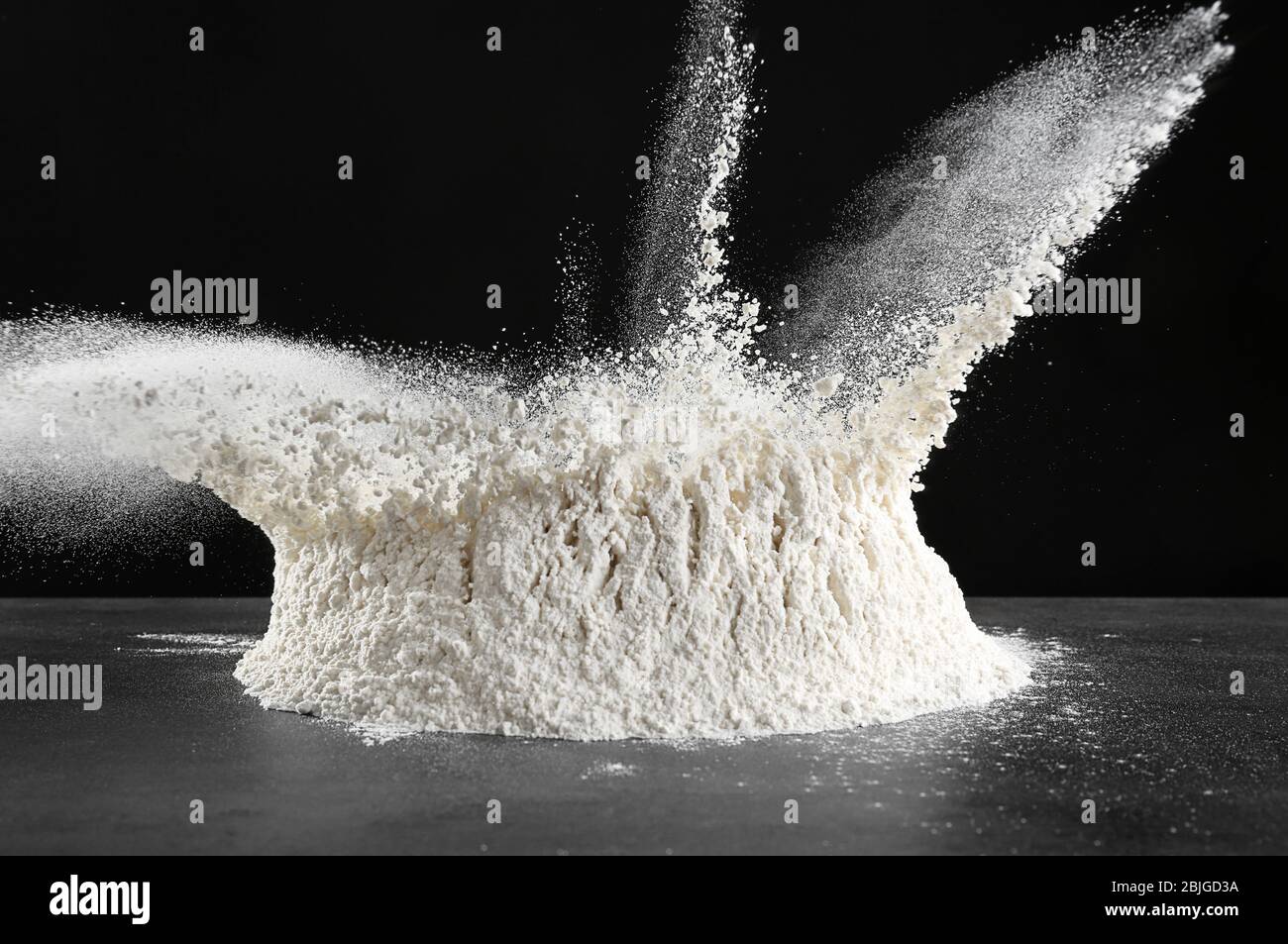 Pile of bursting flour on table against dark background Stock Photo - Alamy