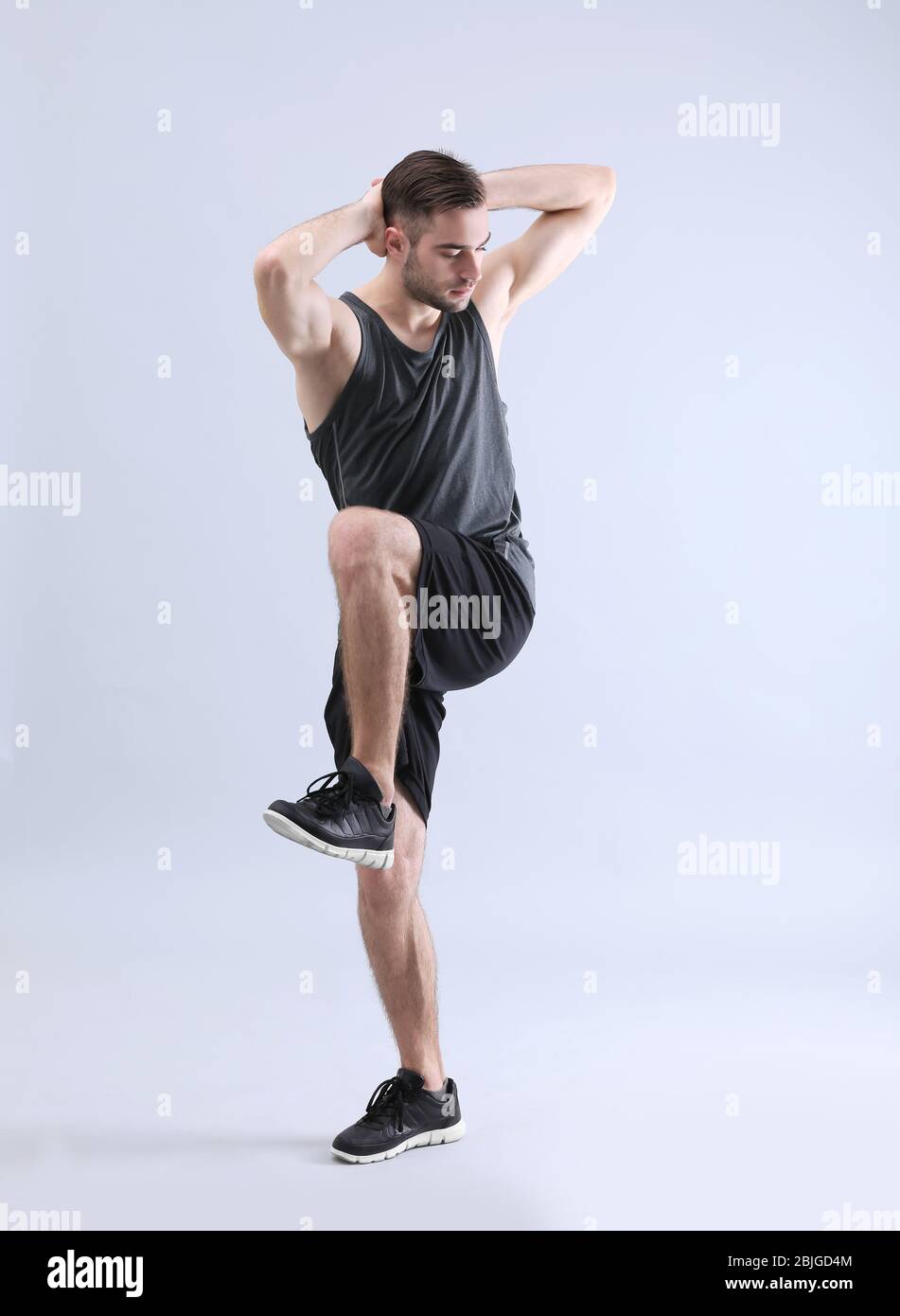 Young man doing bicycle crunch exercise on white background Stock Photo ...
