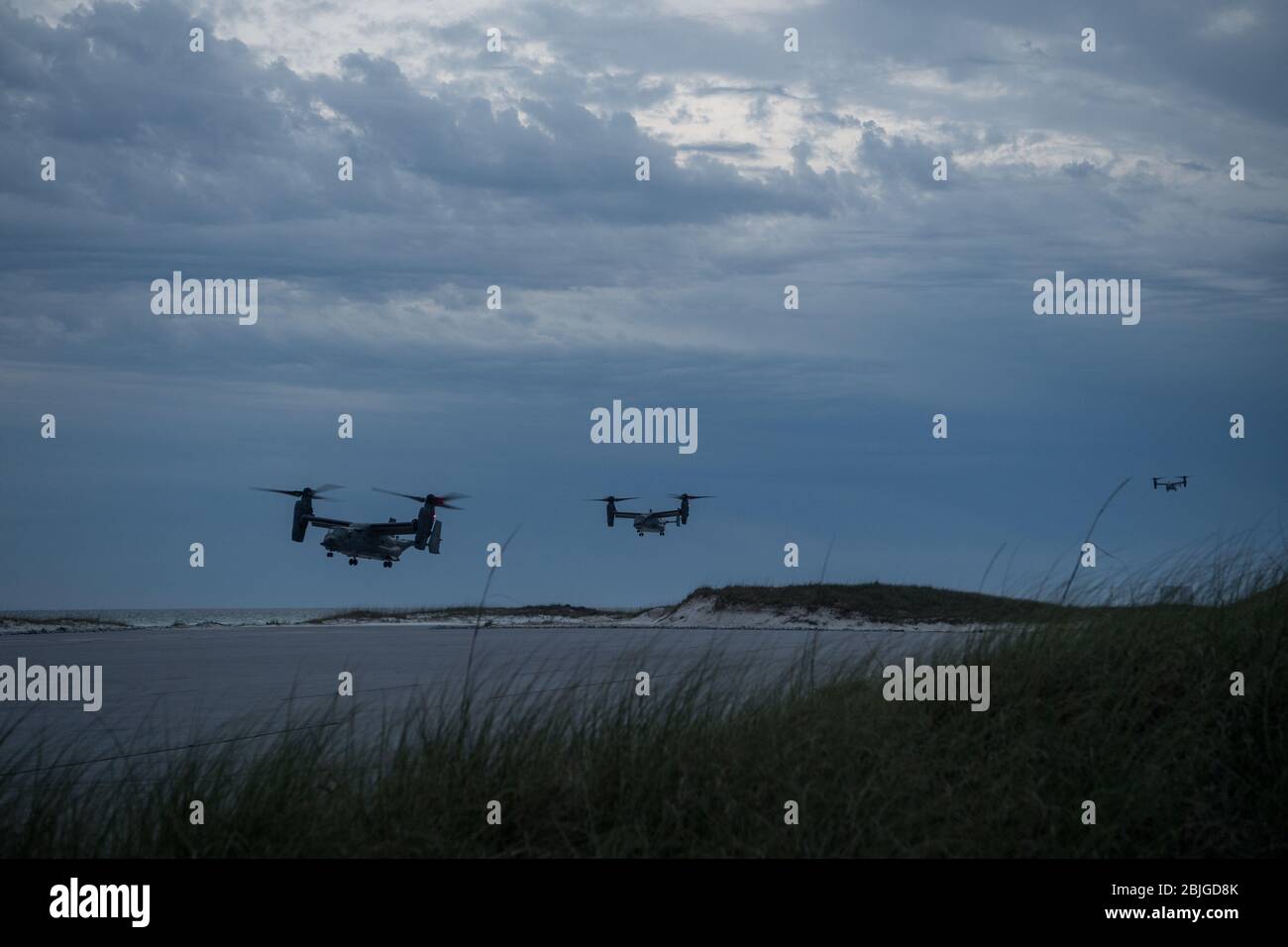 Three CV-22 Osprey tilt-rotator aircraft approach a landing zone for a ...