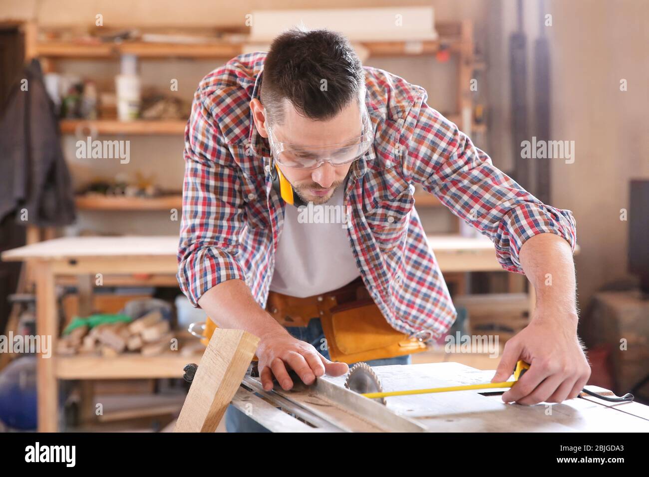 Carpenter taking measurements for working with wooden plank in shop ...