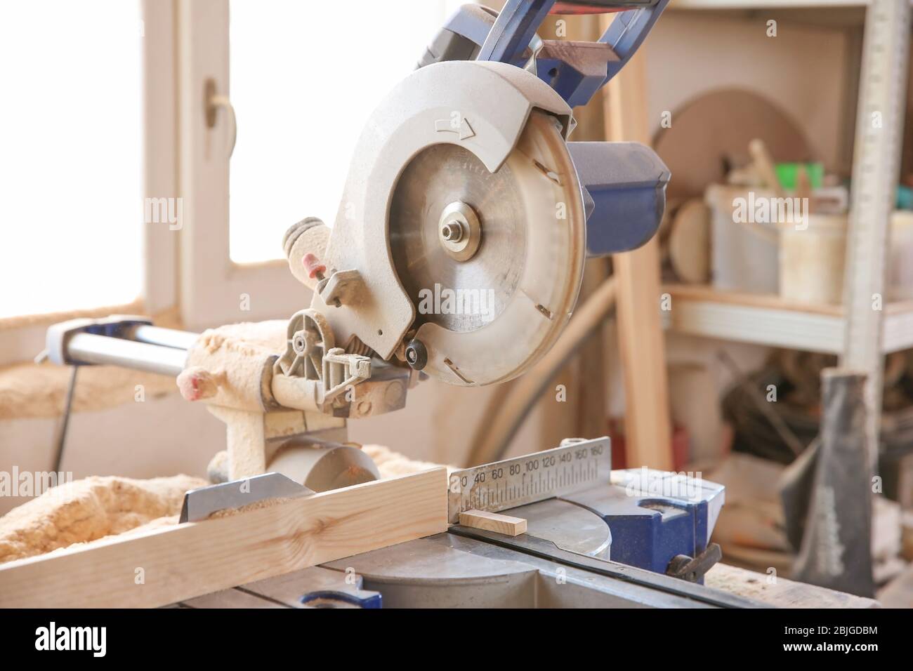 Circular saw and timber strip on table near window in carpenter's ...