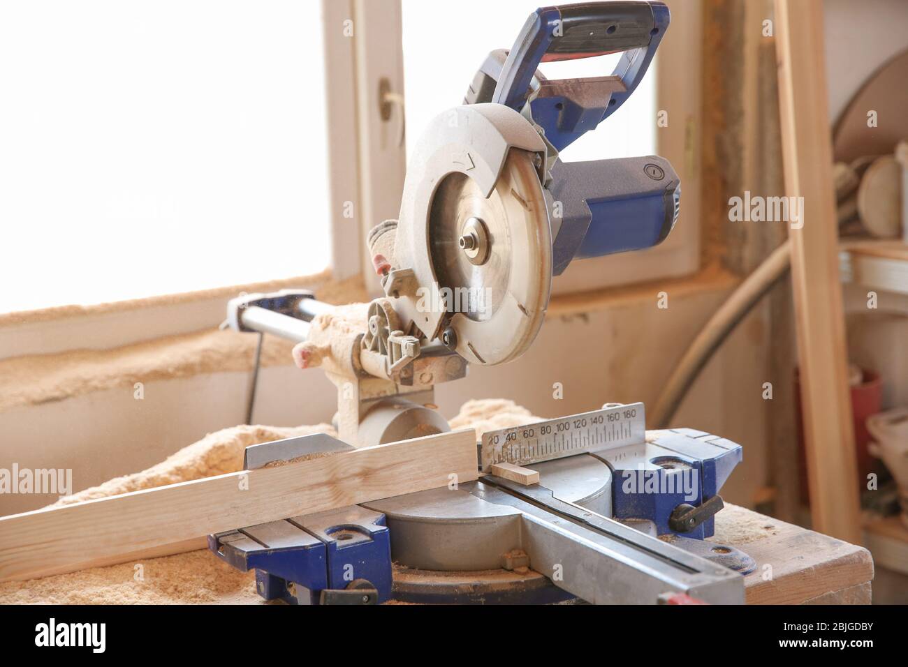 Circular saw and timber strip on table near window in carpenter's ...