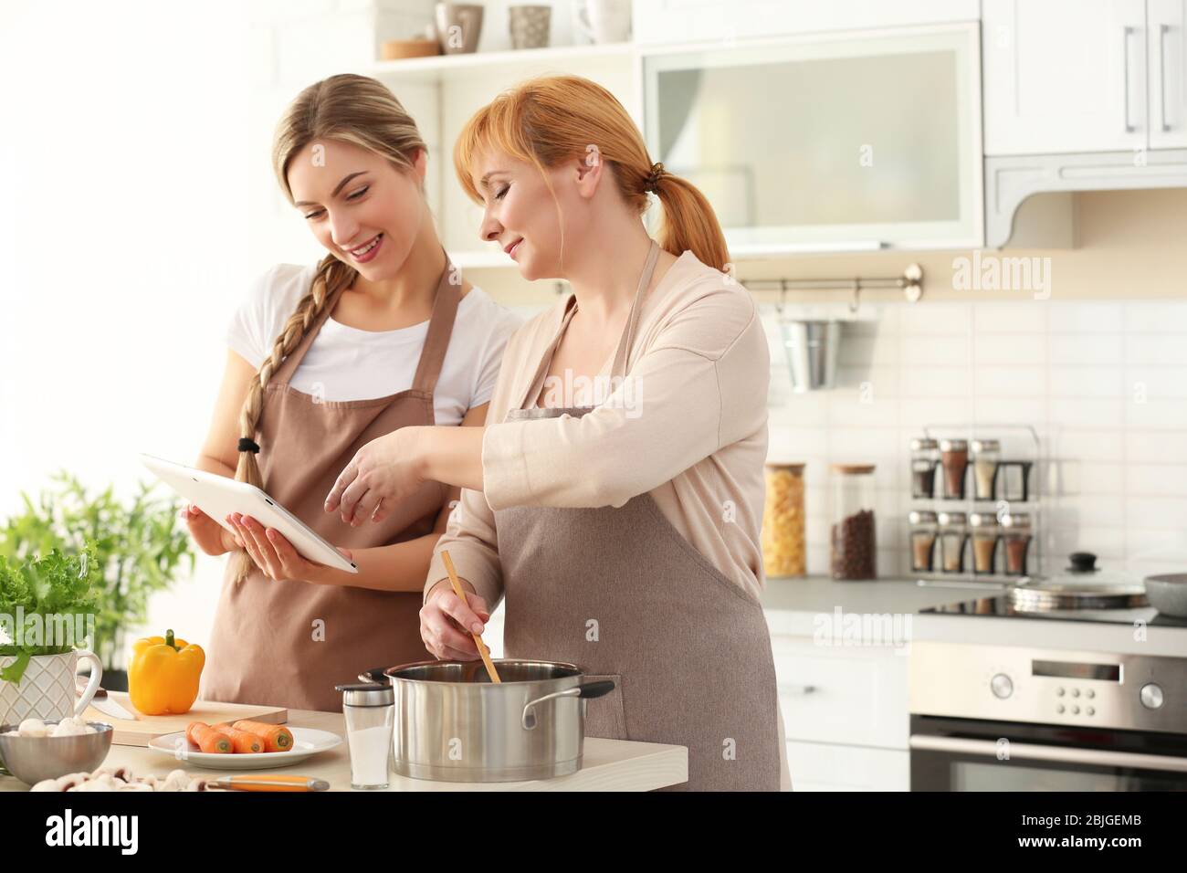 Young woman and her mother cooking in kitchen Stock Photo - Alamy