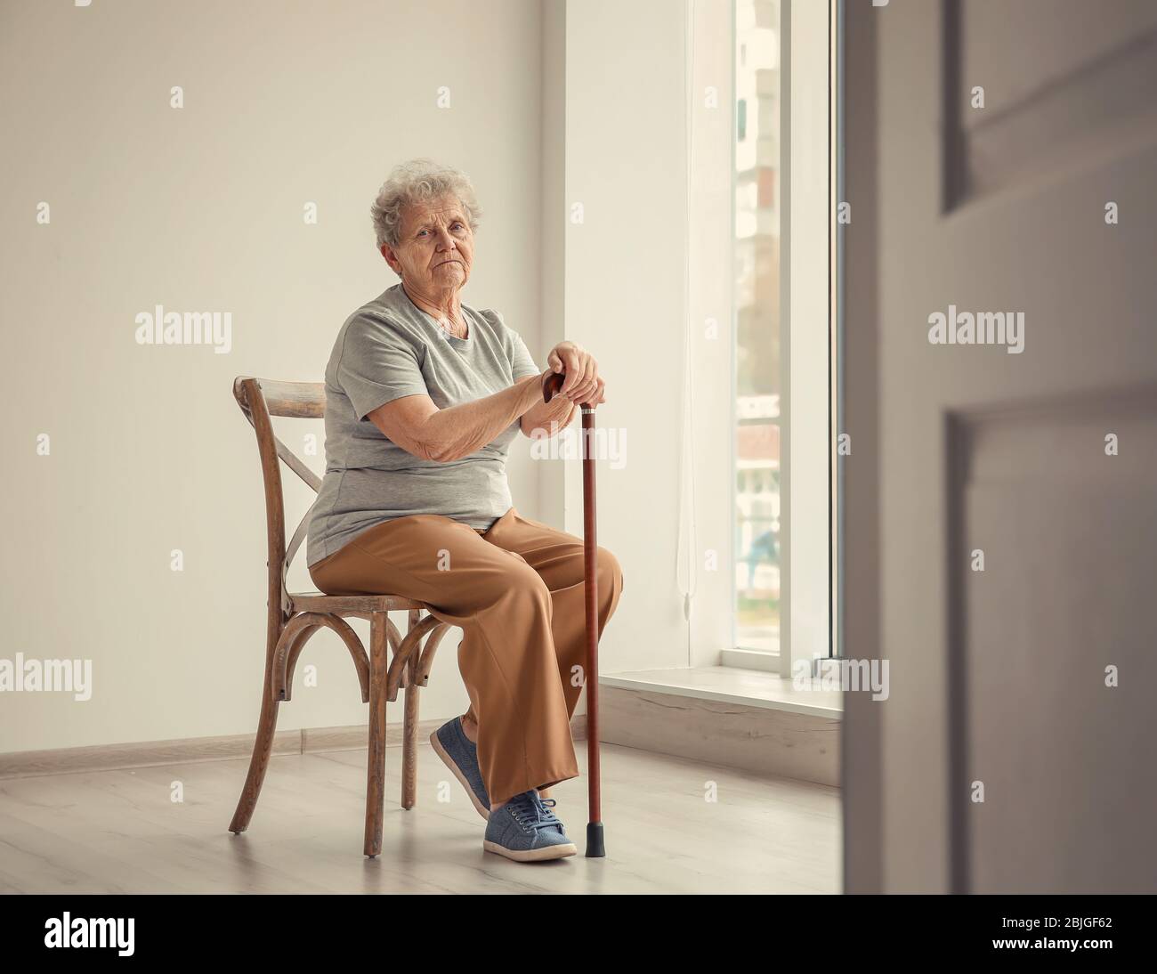 Senior woman sitting on chair in empty room. Poverty concept Stock ...