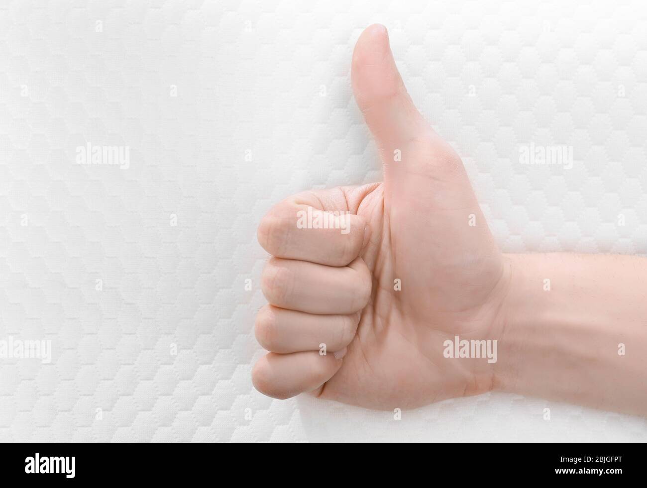 Male hand showing thumb up sign and orthopedic pillow on background ...