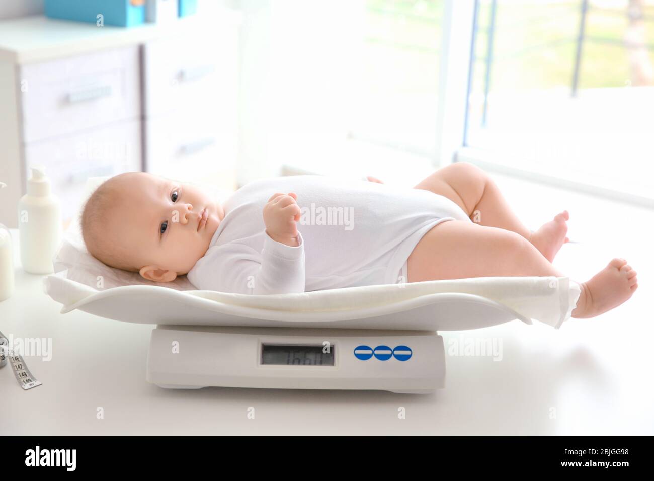 Baby lying on scales in room Stock Photo - Alamy