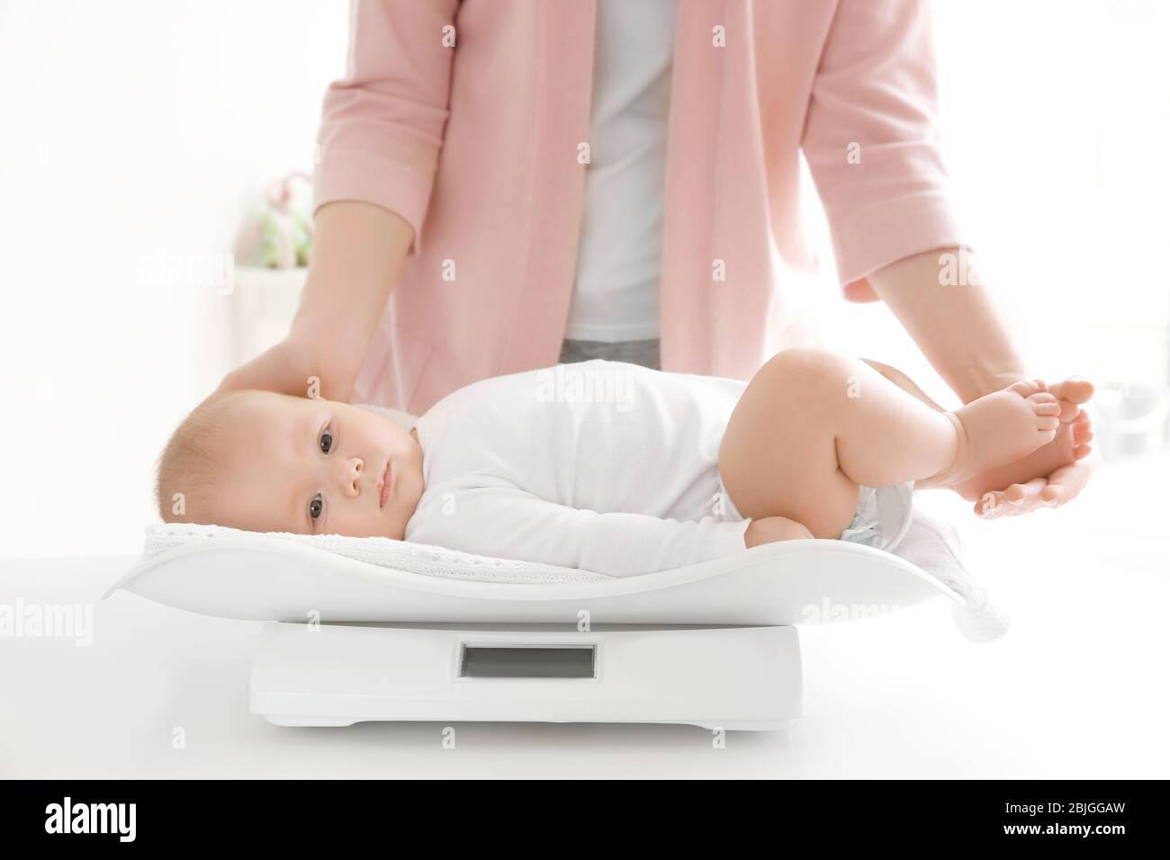 Mother weighting baby on scales in room Stock Photo - Alamy