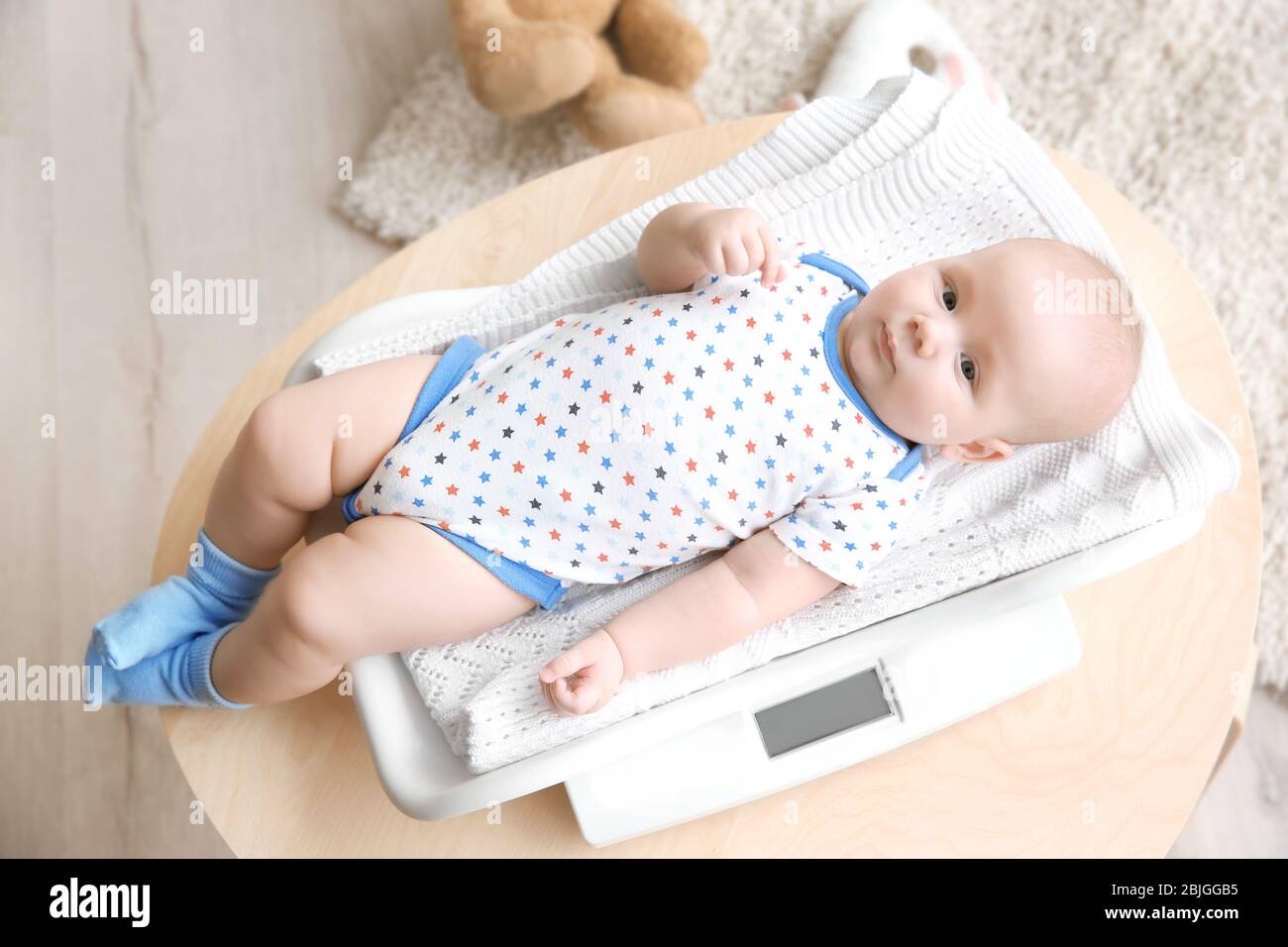 Baby lying on scales in room Stock Photo - Alamy