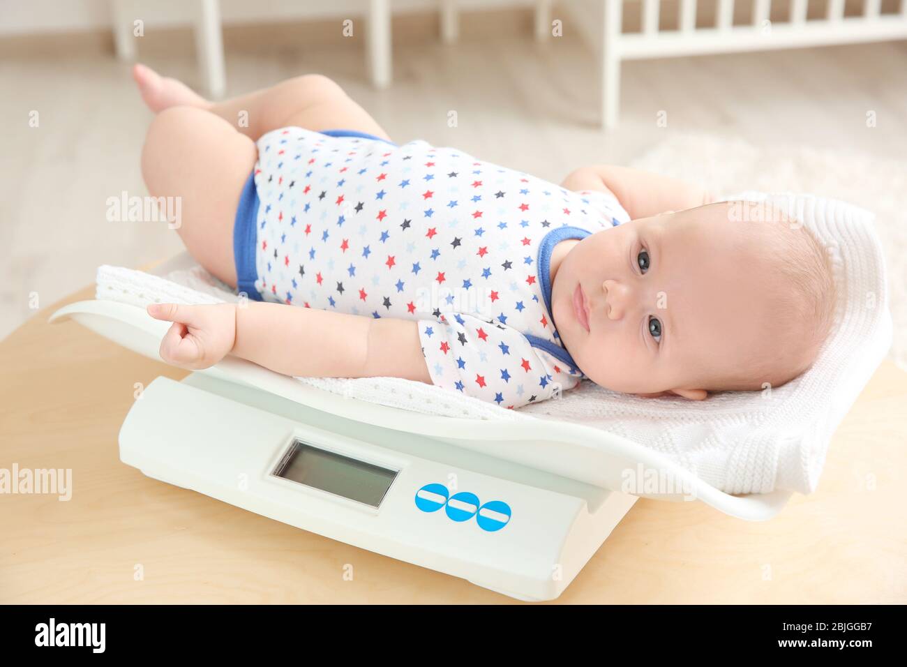 Baby lying on scales in room Stock Photo - Alamy