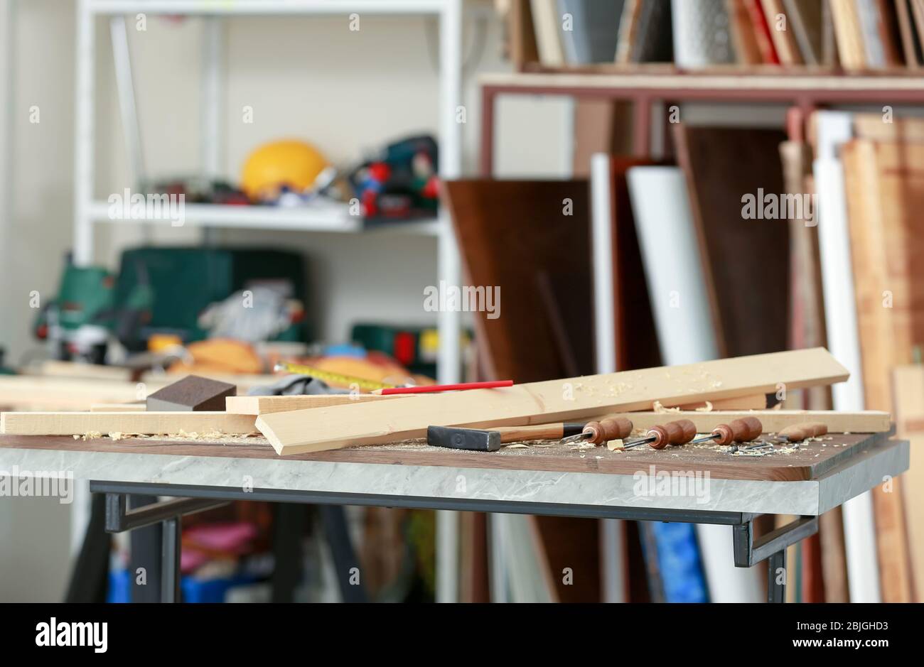 Table with wooden boards and special tools in carpenter's workshop ...