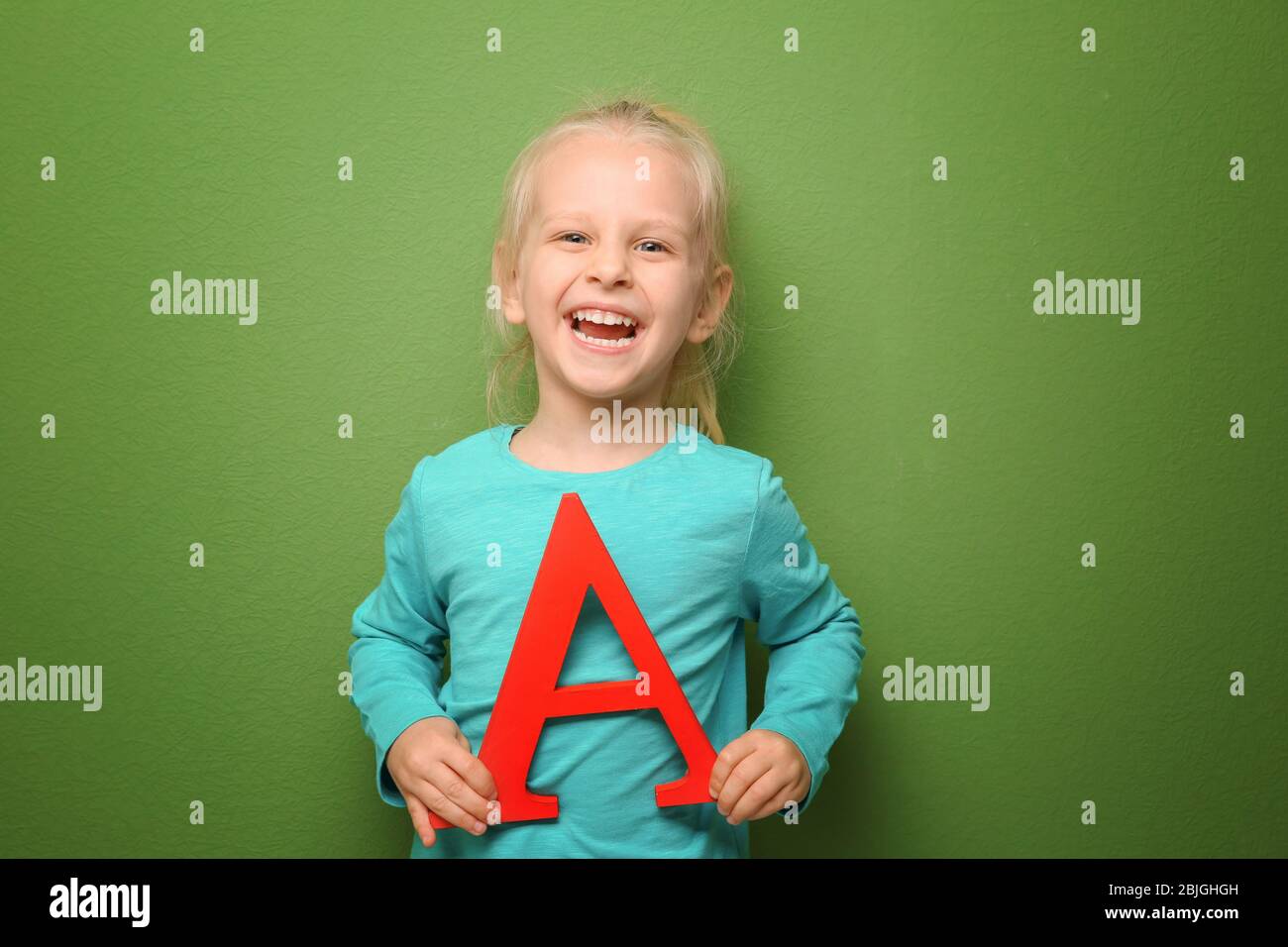 Cute little girl with letter A on color background Stock Photo - Alamy