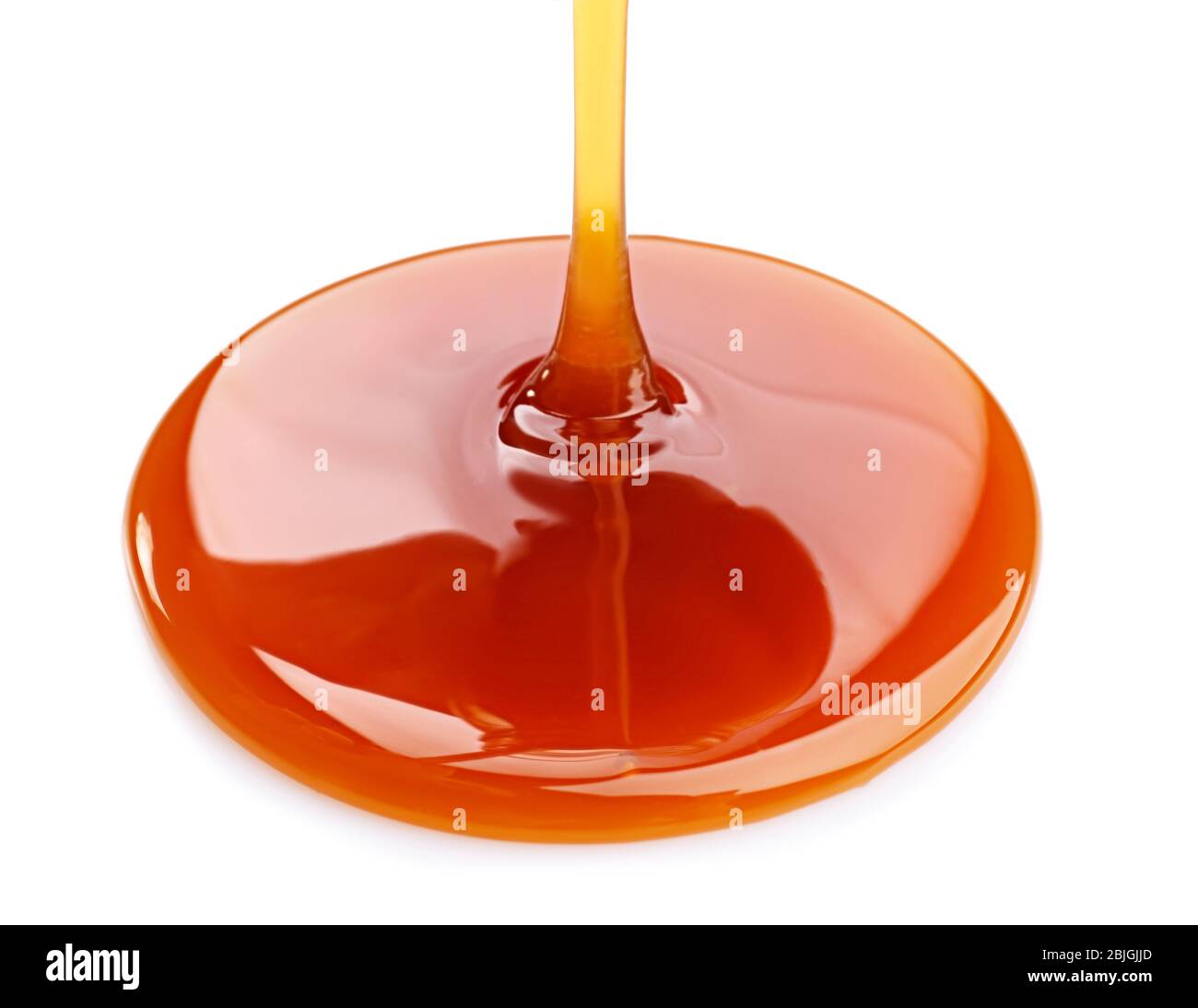 Pouring caramel sauce onto white background Stock Photo - Alamy