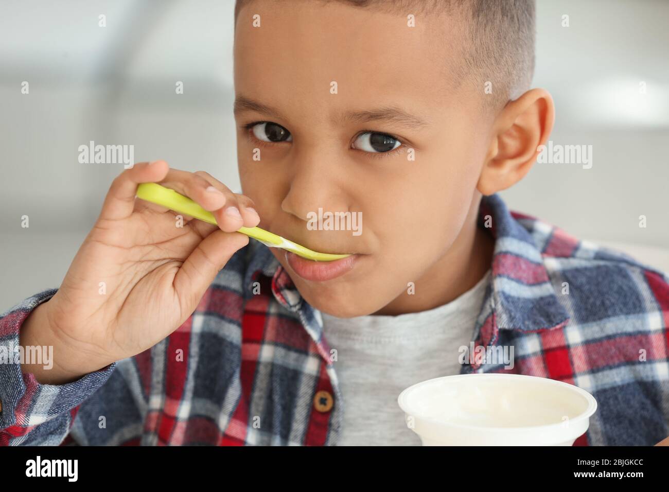 Cute African American boy eating yogurt at home, closeup Stock Photo ...
