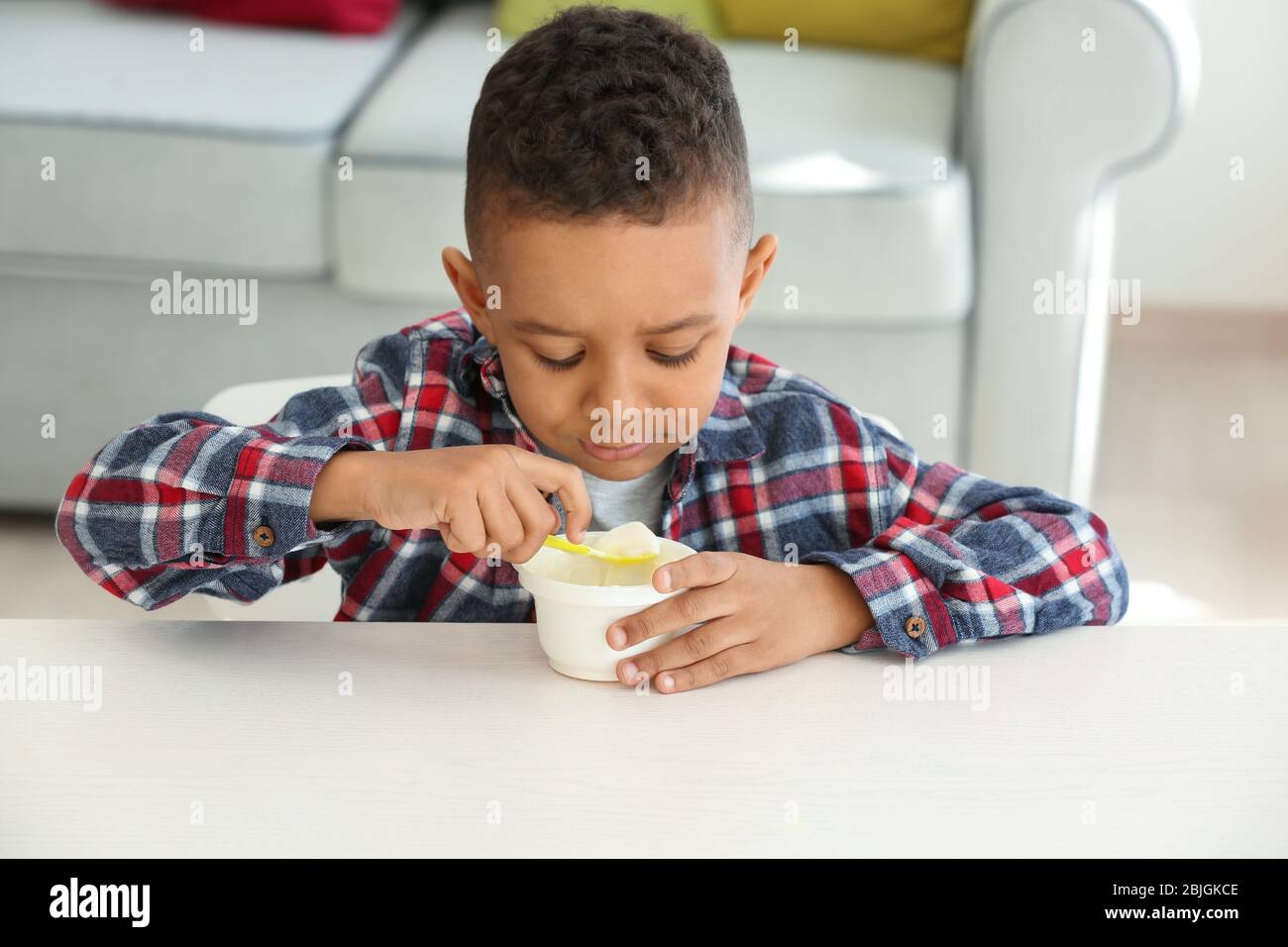 Cute African American boy eating yogurt at home Stock Photo - Alamy