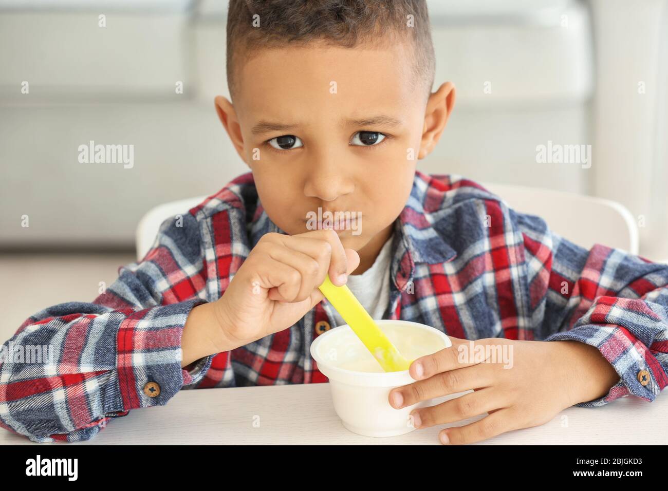 Cute African American boy eating yogurt at home Stock Photo - Alamy