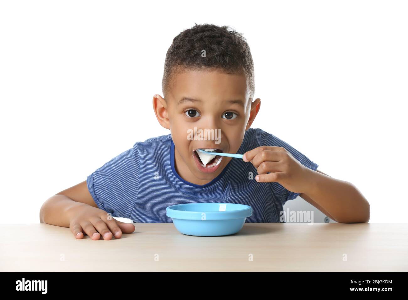 Cute African American boy eating yogurt on white background Stock Photo ...