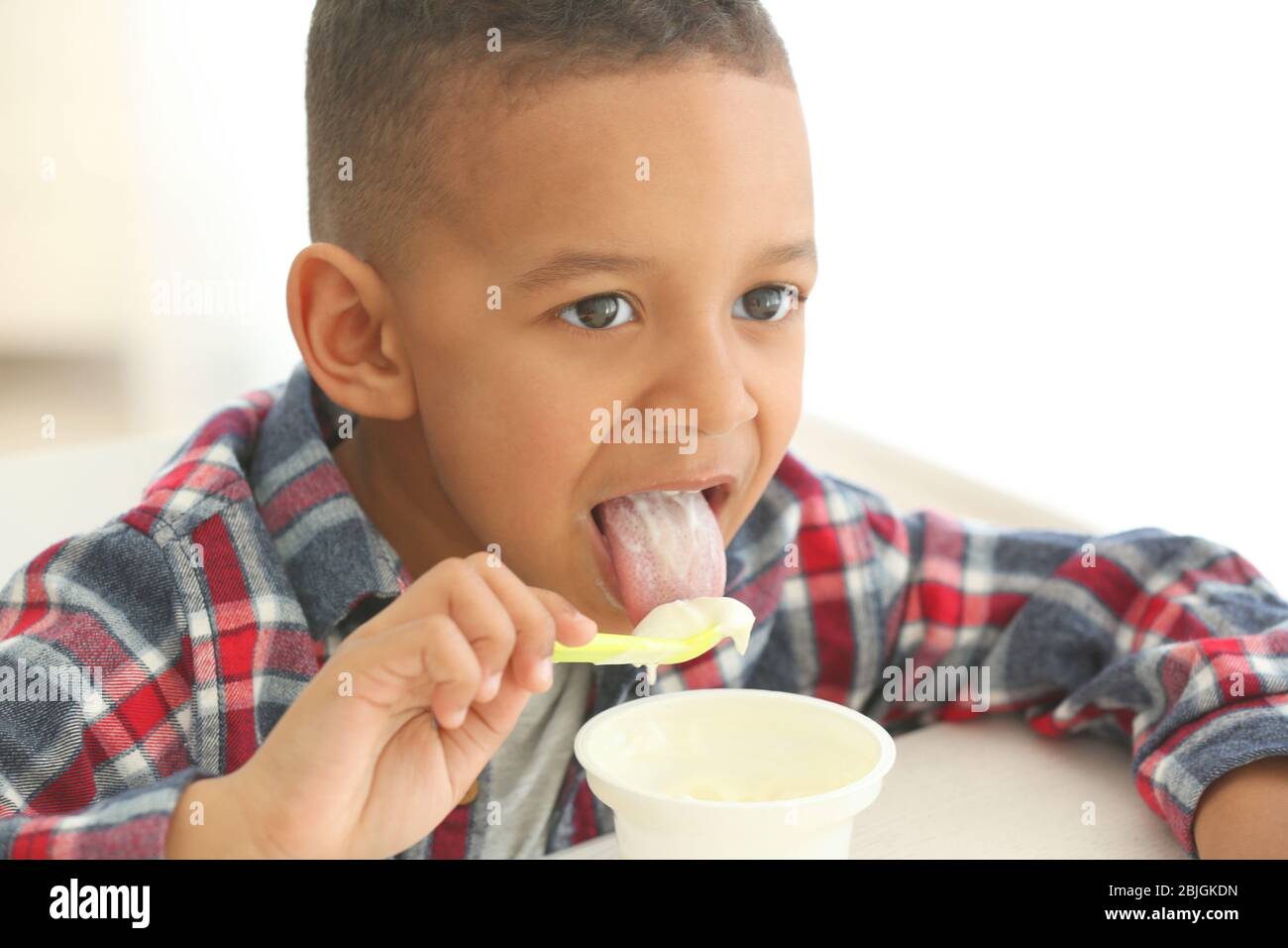 Cute African American boy eating yogurt at home, closeup Stock Photo ...