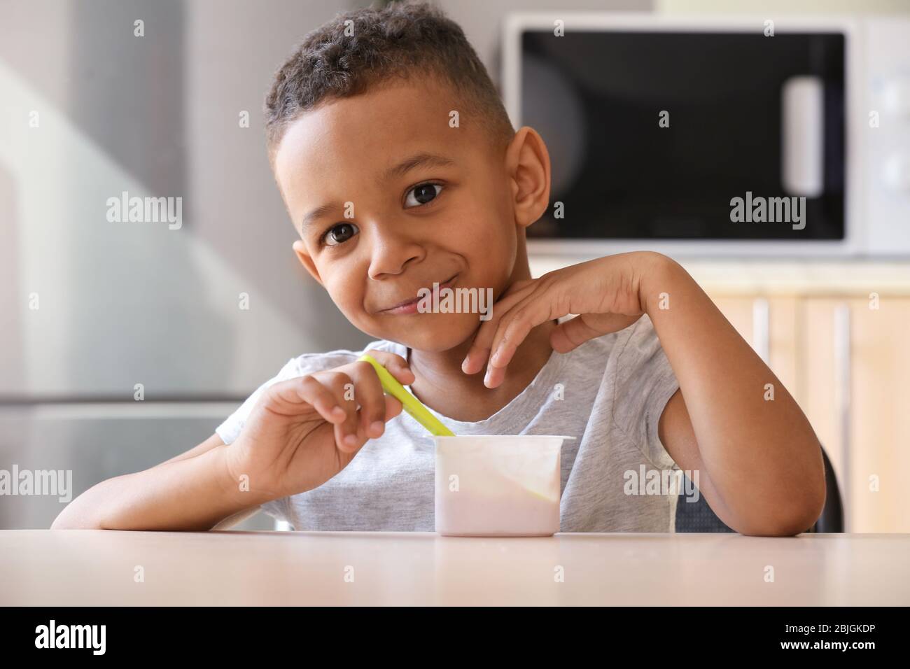 Cute African American boy eating yogurt at home Stock Photo - Alamy
