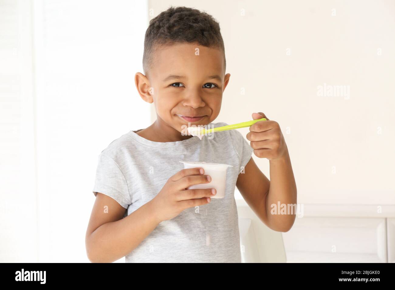 Cute African American boy eating yogurt at home Stock Photo - Alamy