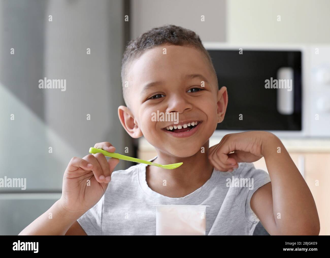 Cute African American boy eating yogurt at home Stock Photo - Alamy