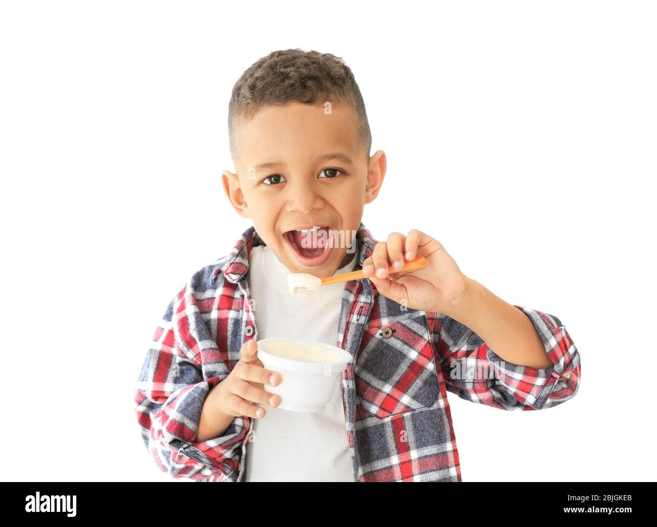 Cute African American boy eating yogurt on light background Stock Photo ...