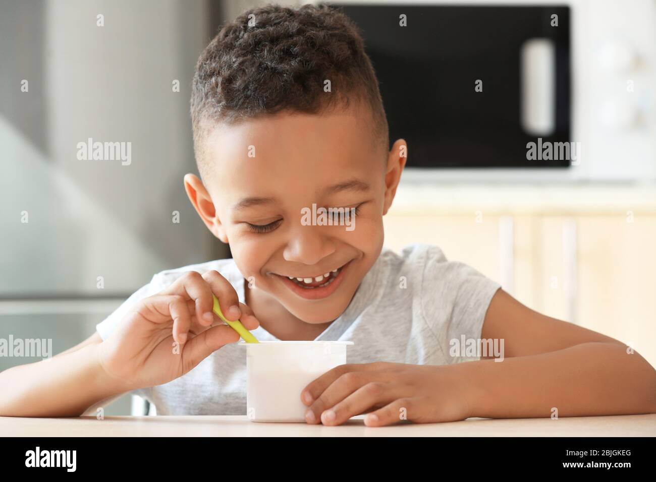 Cute African American boy eating yogurt at home Stock Photo - Alamy