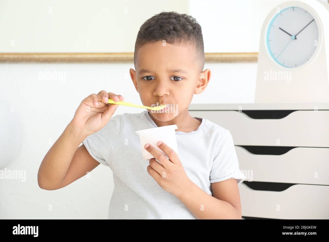 Cute African American boy eating yogurt at home Stock Photo - Alamy