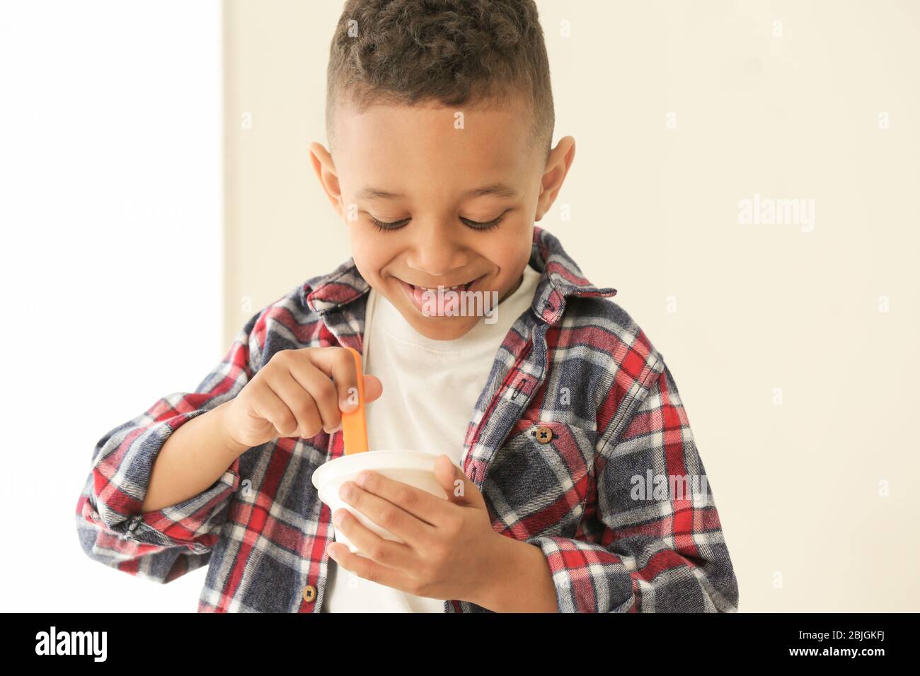 Cute African American boy eating yogurt at home Stock Photo - Alamy