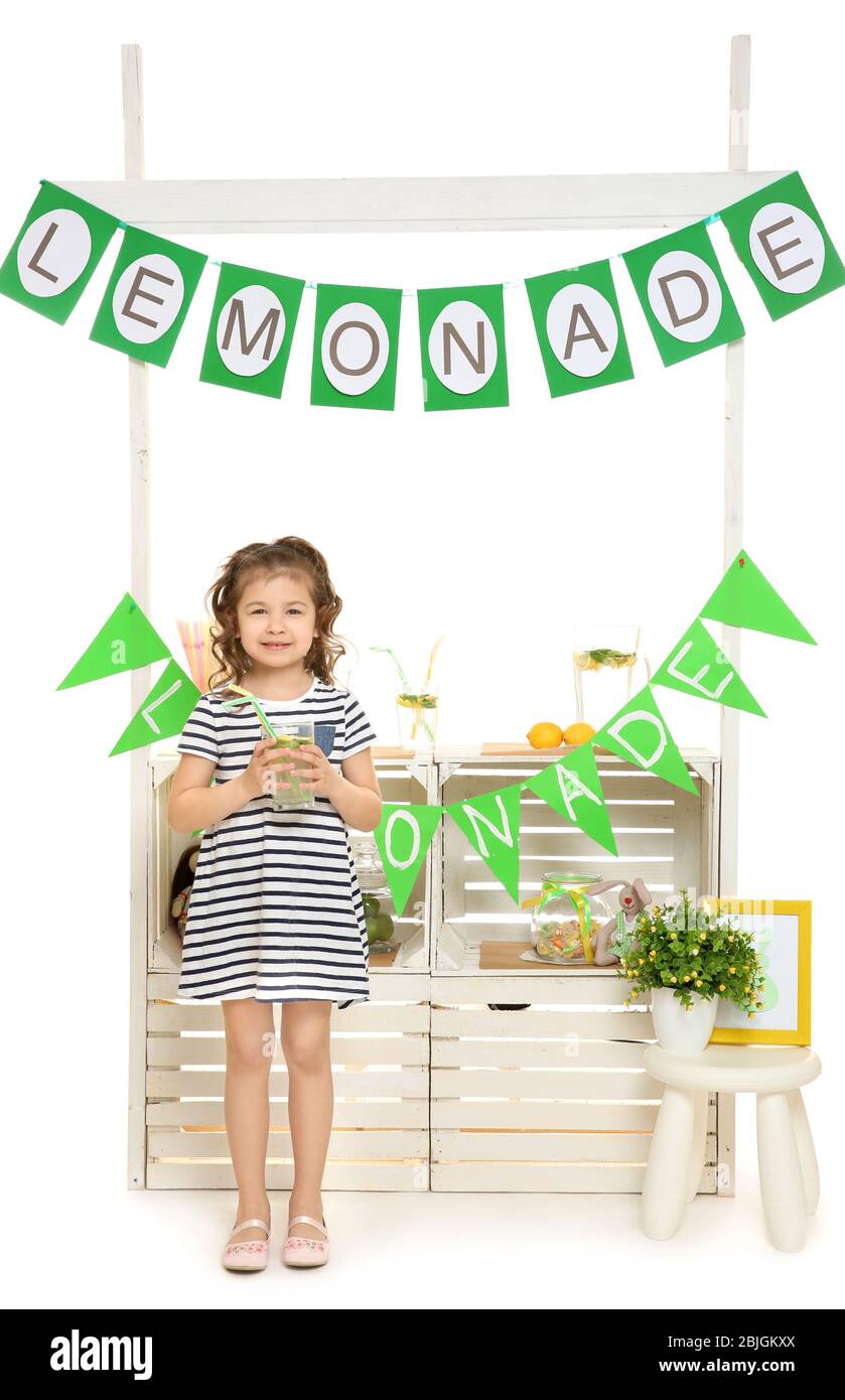 Cute little girl standing near counter with lemonade on white ...