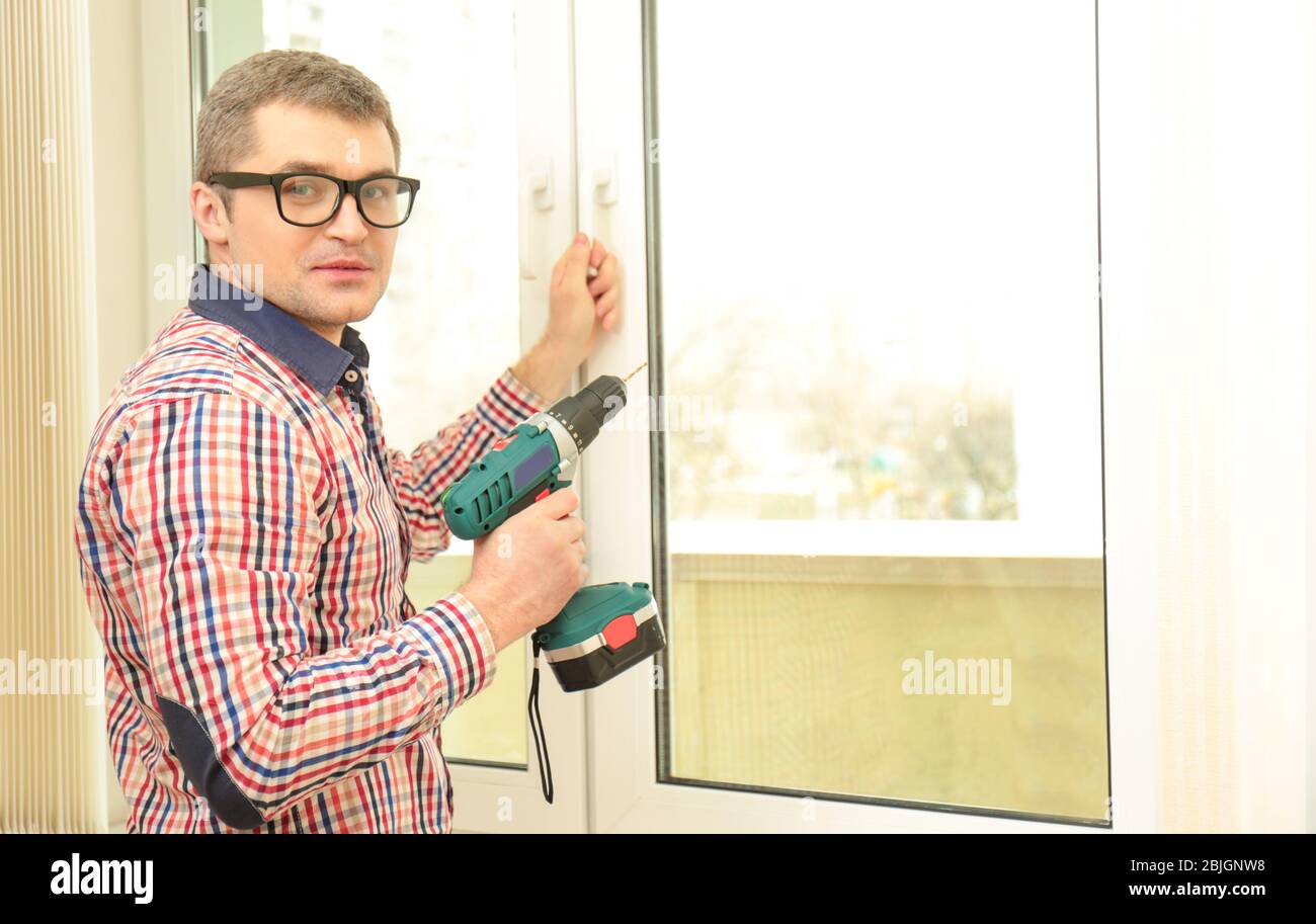 Young man installing window shades at home Stock Photo - Alamy