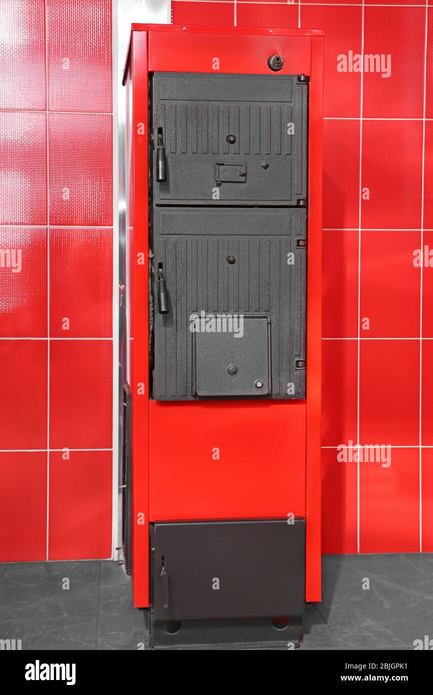 Solid fuel boiler against red wall Stock Photo - Alamy