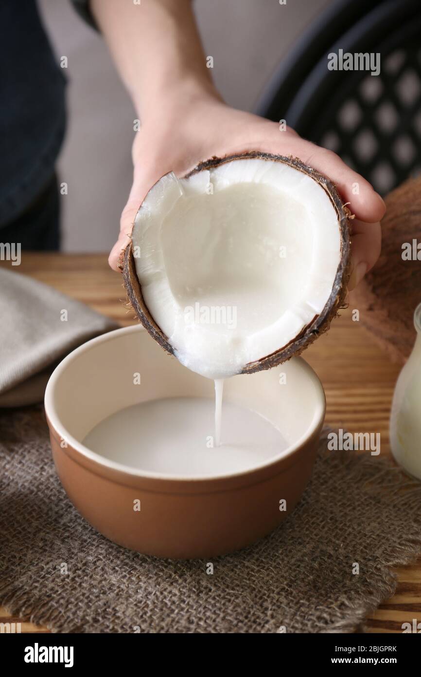 Woman pouring coconut cream into bowl on table Stock Photo - Alamy