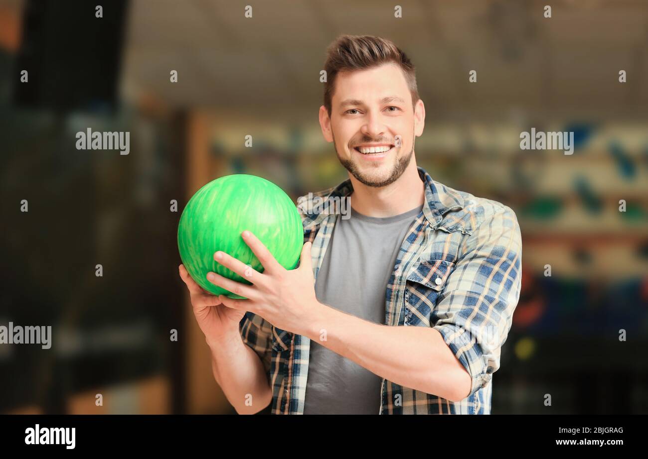 Handsome young man with ball in bowling club Stock Photo - Alamy