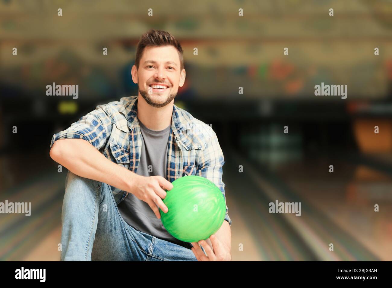 Handsome young man with ball in bowling club Stock Photo - Alamy