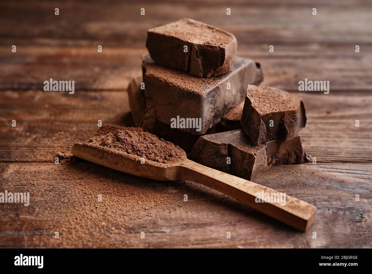 Scoop with cocoa powder and chopped chocolate chunks on wooden table ...