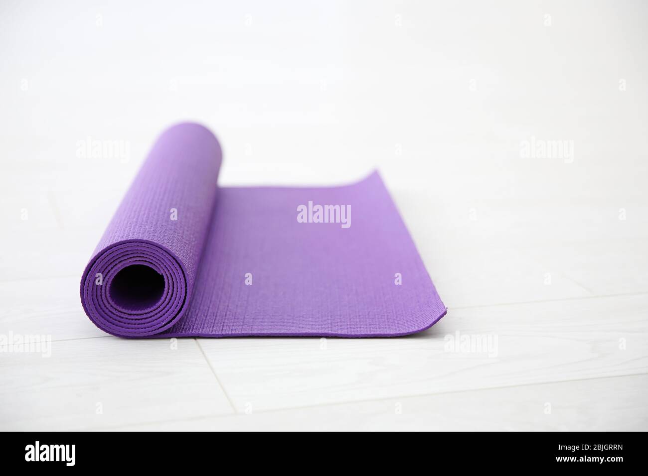 Purple yoga mat on light background Stock Photo - Alamy