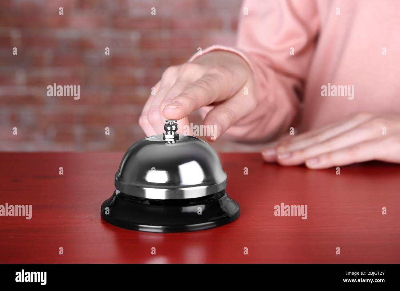 Woman ringing service bell in hotel lobby Stock Photo - Alamy