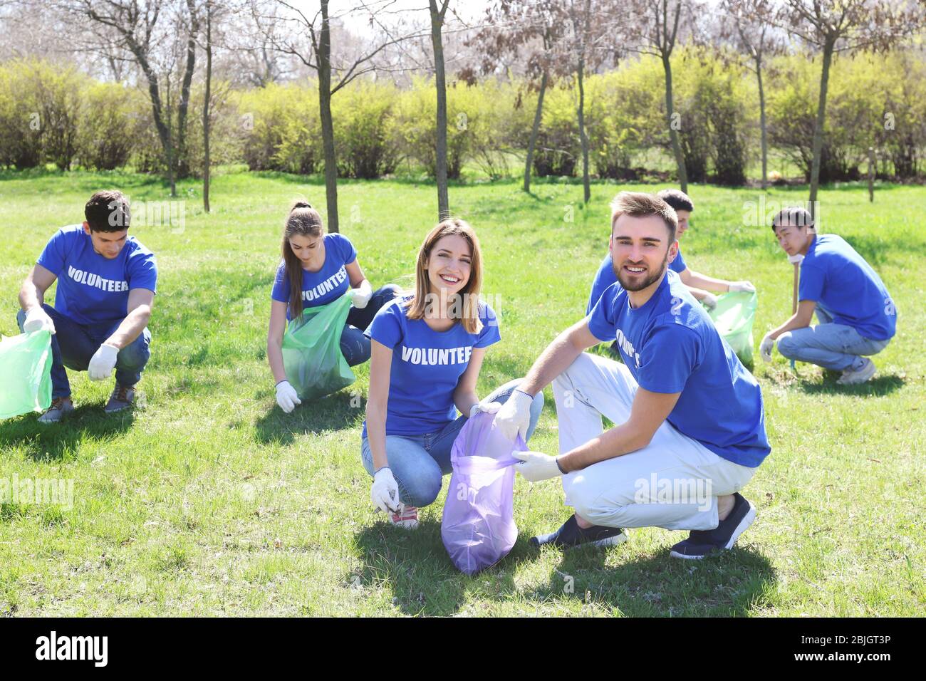 Group of young volunteers gathering garbage in park Stock Photo - Alamy