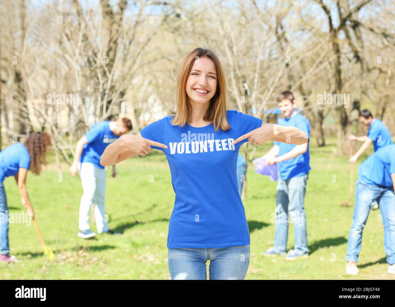 Beautiful young volunteer with team outdoors Stock Photo - Alamy
