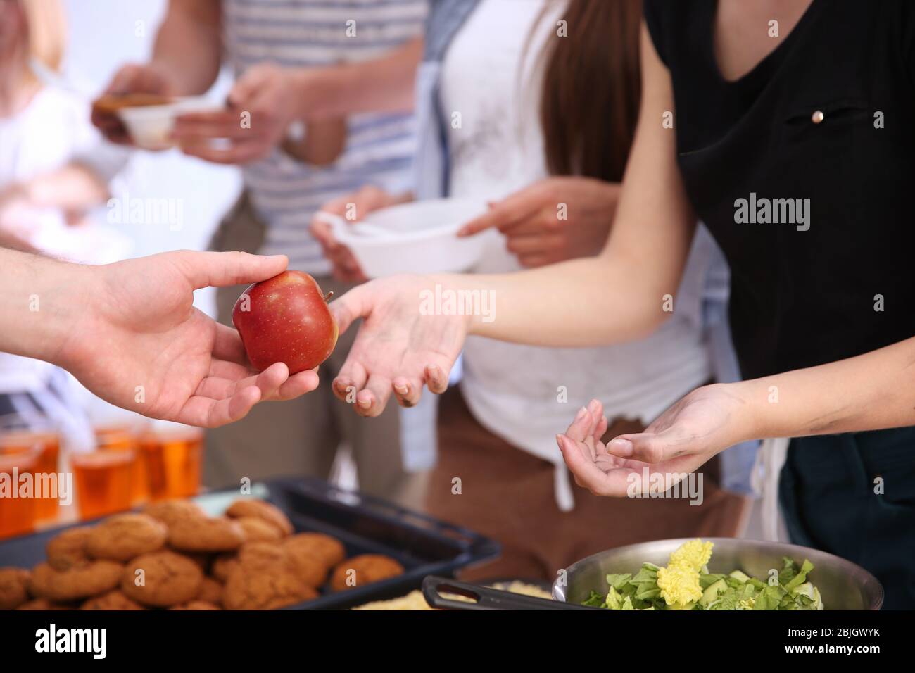 Volunteer giving apple to poor woman. Poverty concept Stock Photo - Alamy
