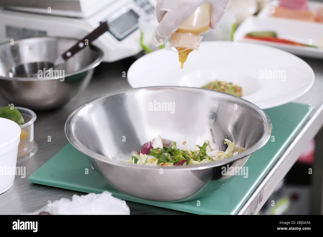 Female chef dressing salad in kitchen Stock Photo - Alamy