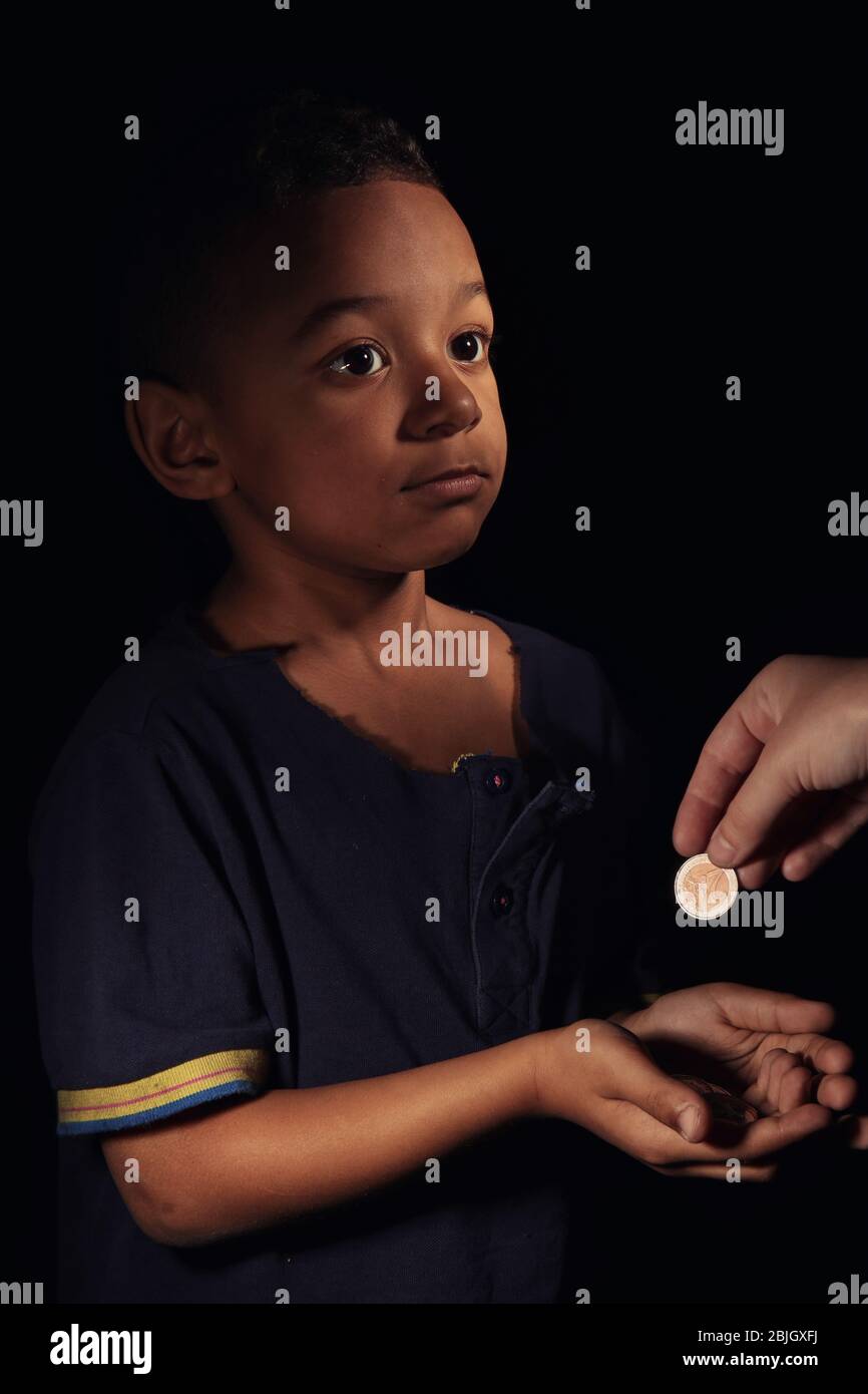 Cute little boy asking for handout on dark background. Poverty concept ...