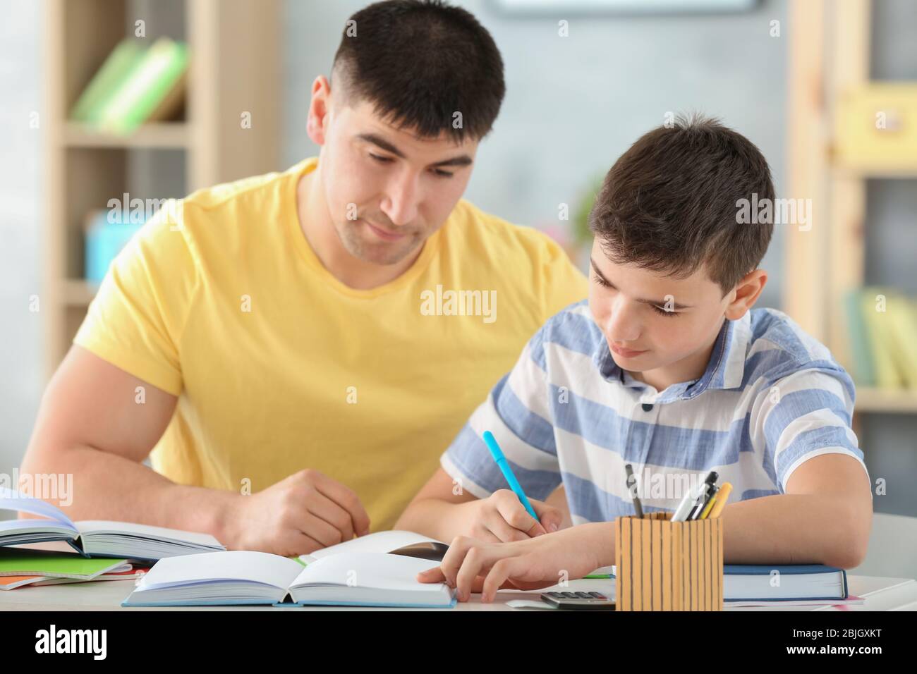 Father and son doing homework together indoors Stock Photo - Alamy